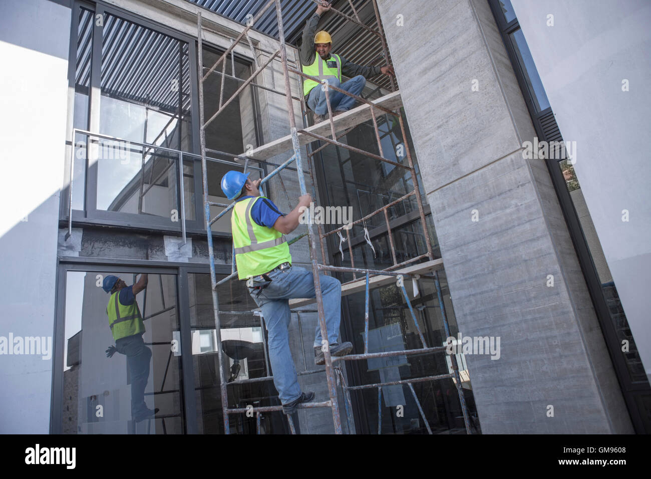 Two construction workers on scaffolding working on construction site ...