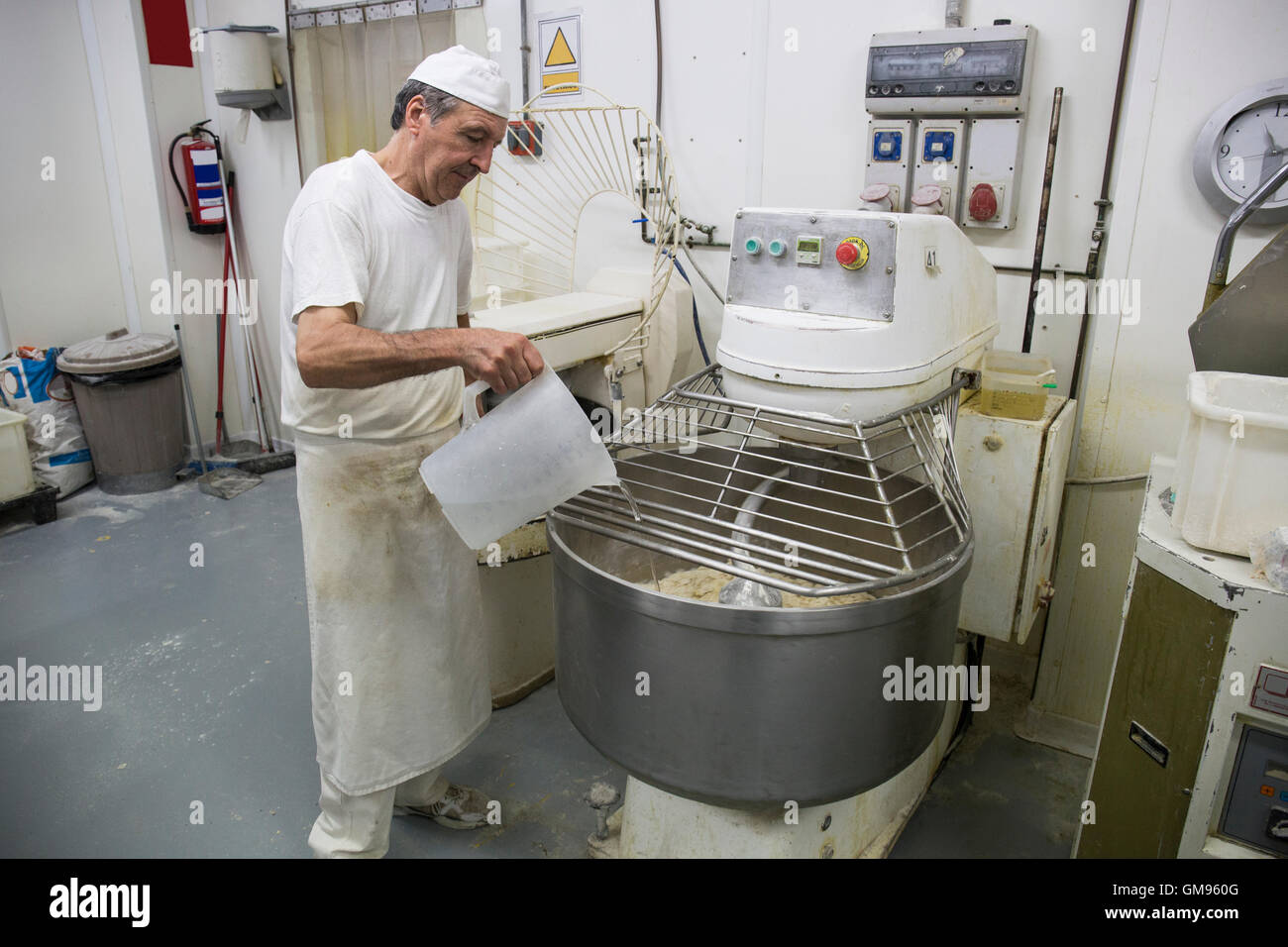 Baker pouring water in an industrial kneading machine Stock Photo - Alamy