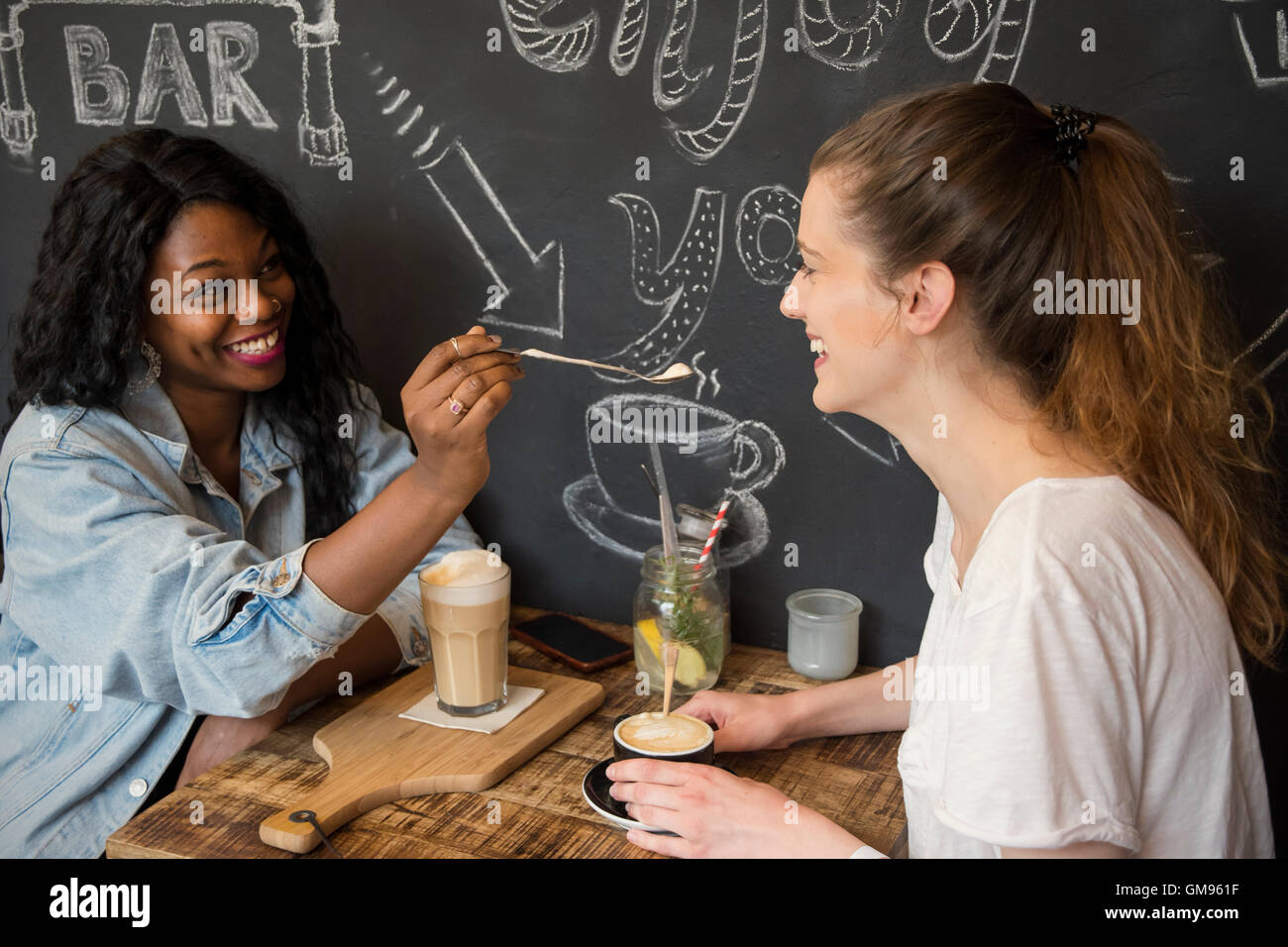 Two friends meeting in cafe, sharing coffee Stock Photo - Alamy