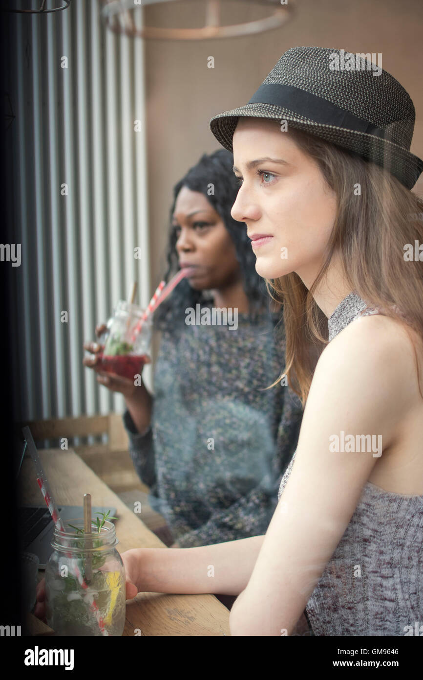 Friends sitting in a cafe, looking out of window Stock Photo - Alamy