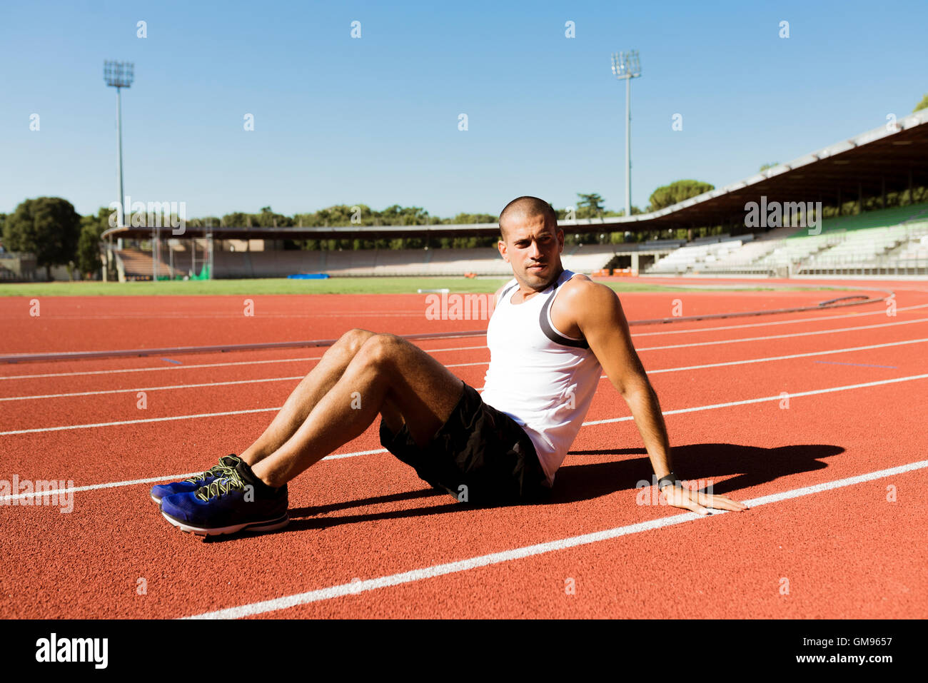 Young sportsman sitting on running track Stock Photo - Alamy