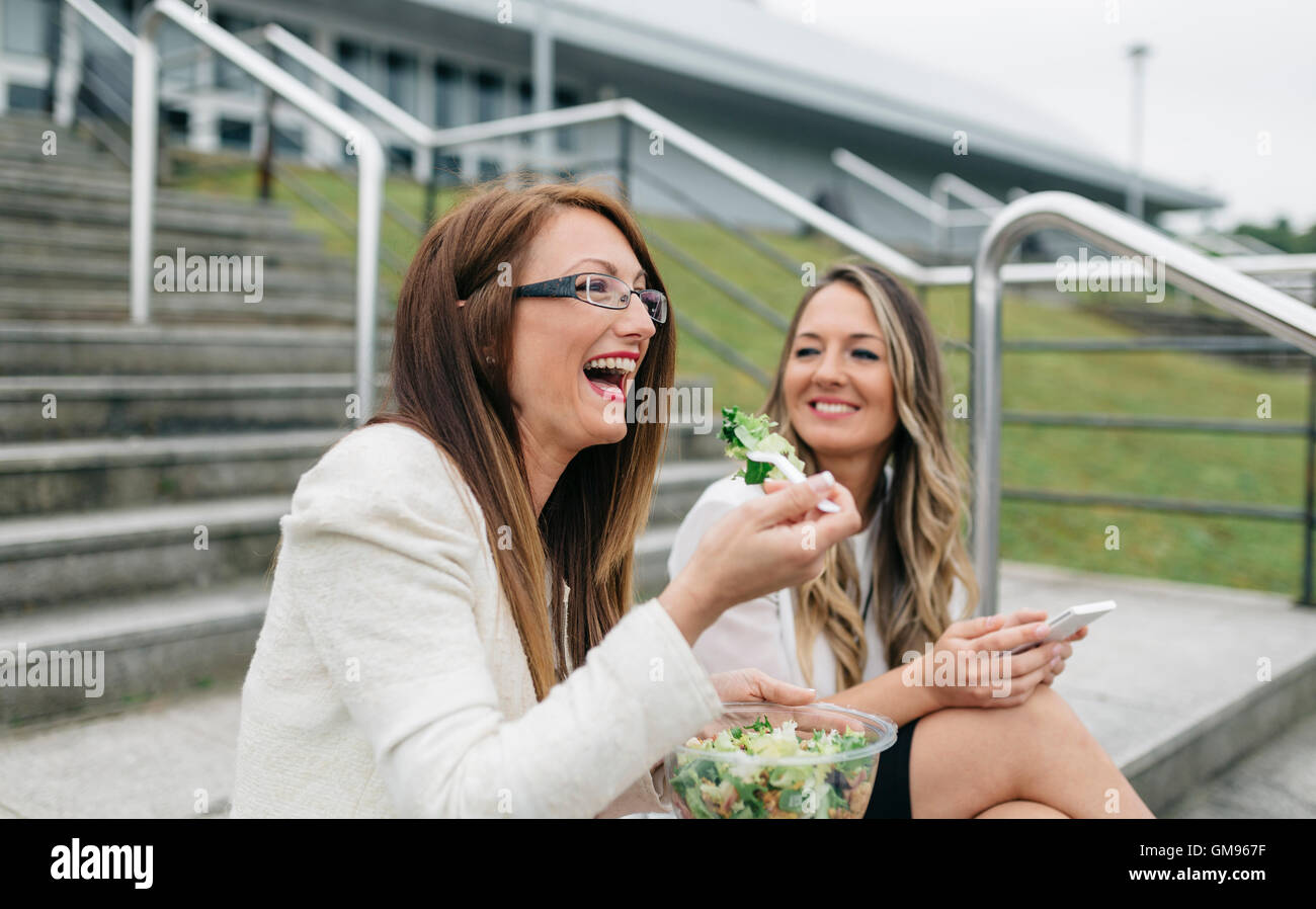 Two laughing women having lunch break outdoors Stock Photo - Alamy