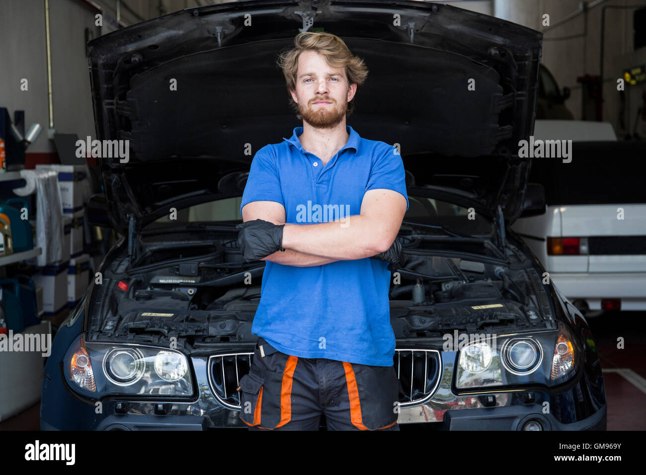 Mechanic standing in his car workshop with arms crossed Stock Photo - Alamy