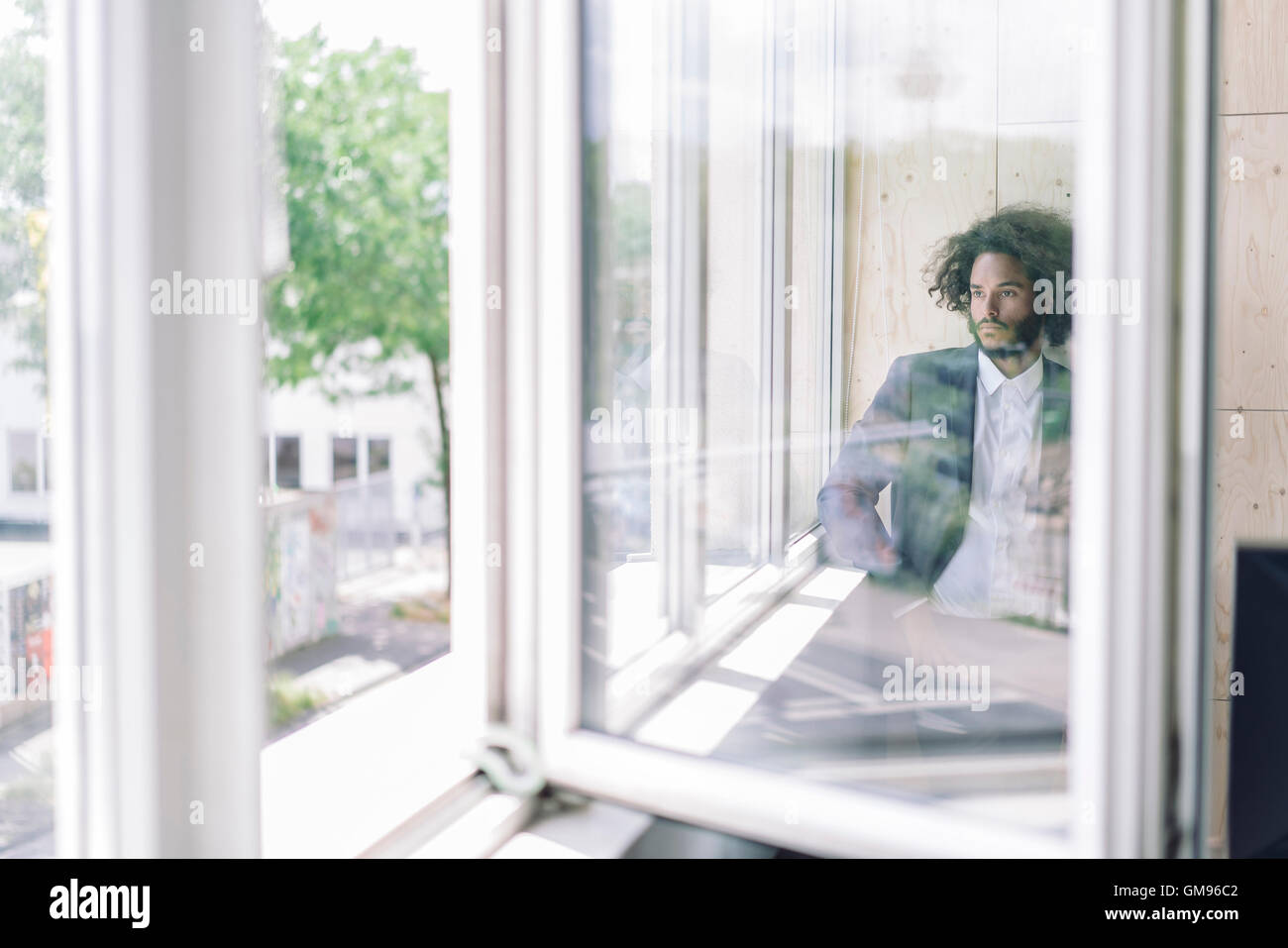 Young businessman standing by window, thinking Stock Photo - Alamy