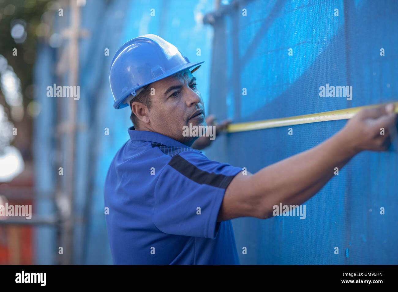 Construction worker measuring on construction site Stock Photo - Alamy