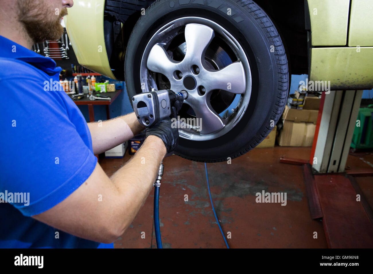 Mechanic fixing a car wheel in a workshop Stock Photo - Alamy