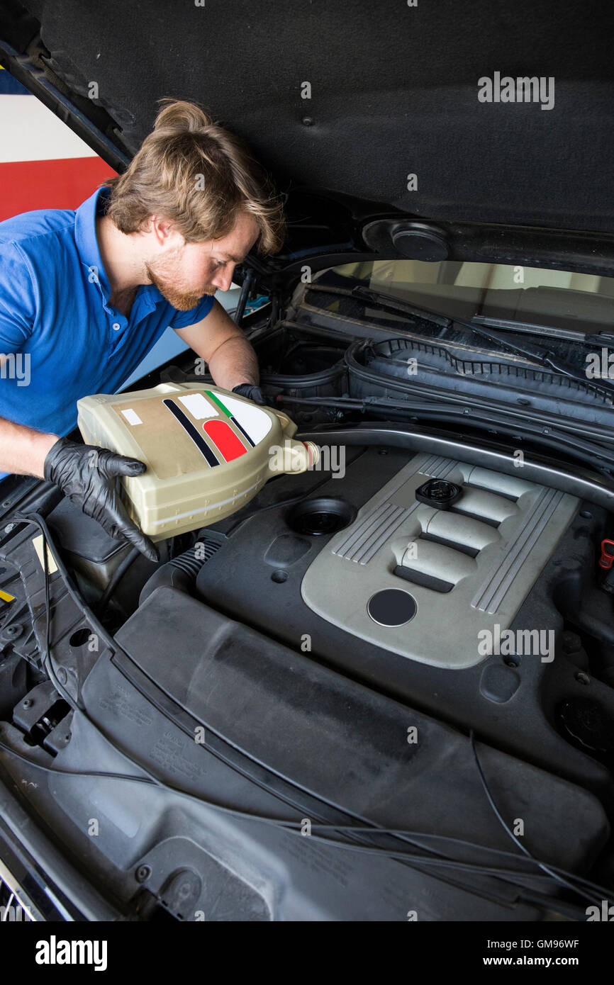 Mechanic refilling oil in a car Stock Photo - Alamy