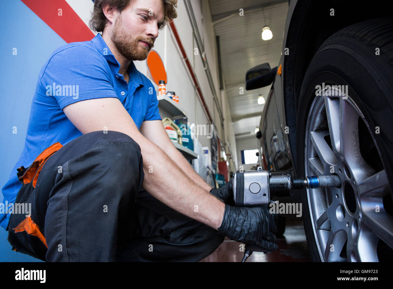 Mechanic fixing a car wheel in a workshop Stock Photo - Alamy