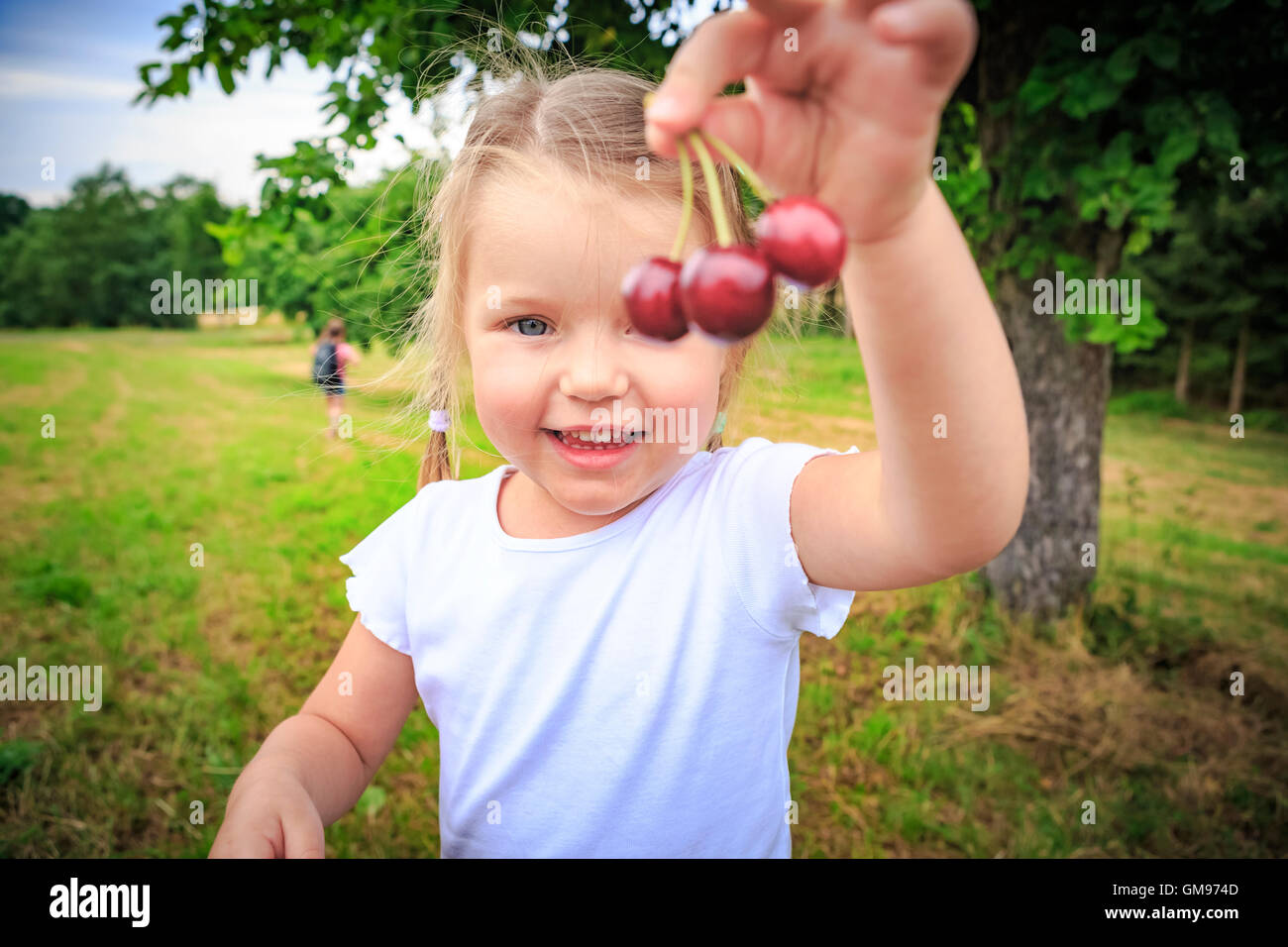 Happy little girl showing cherries Stock Photo - Alamy