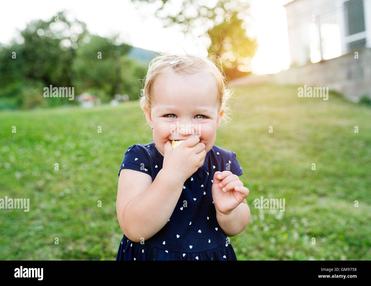 Portrait of little blond girl eating pastry Stock Photo - Alamy