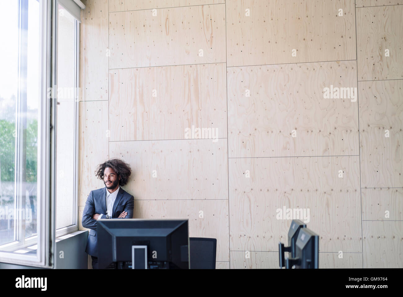 Young businessman standing by window, thinking Stock Photo - Alamy