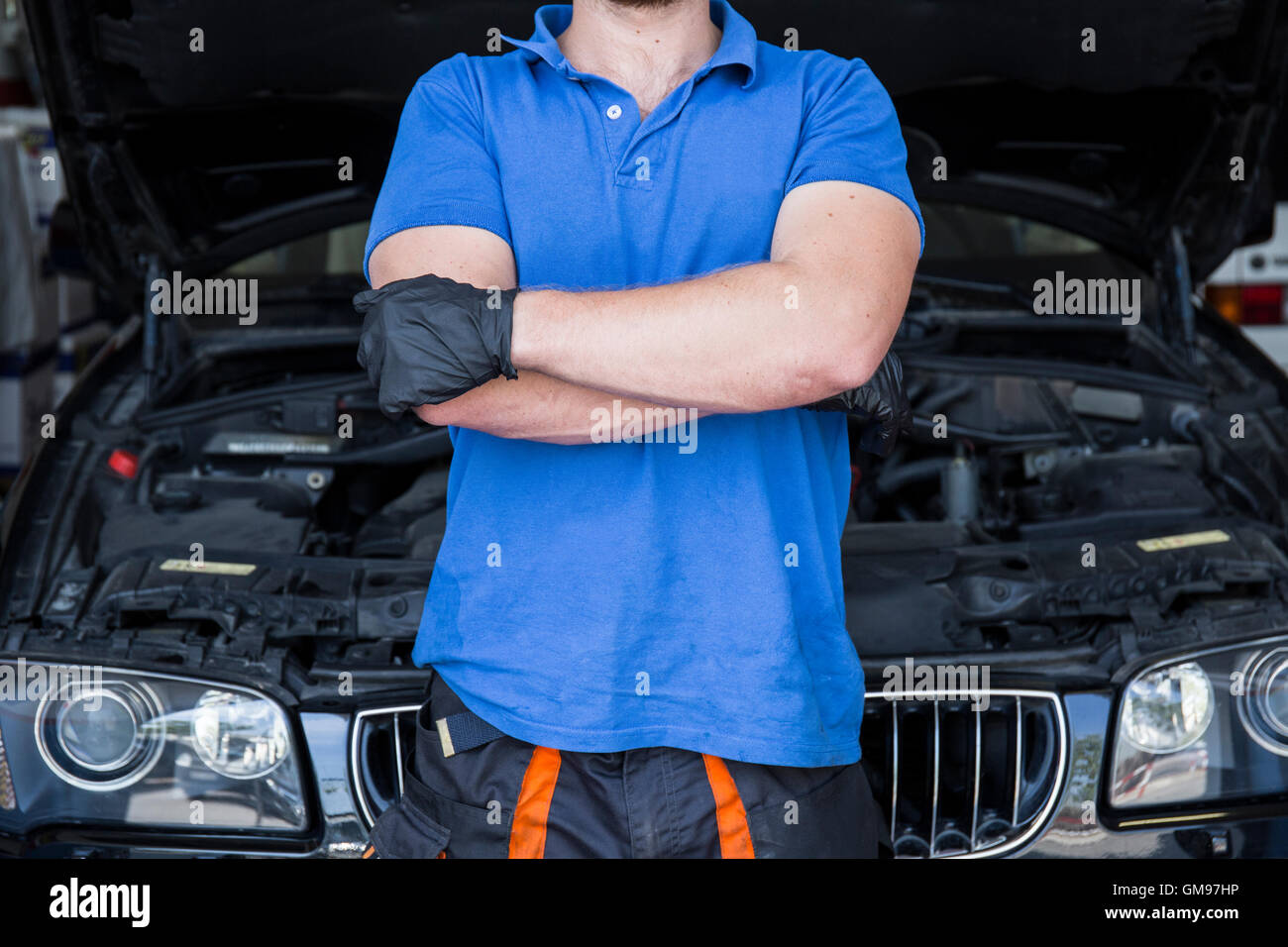 Mechanic standing in his car workshop with arms crossed Stock Photo - Alamy