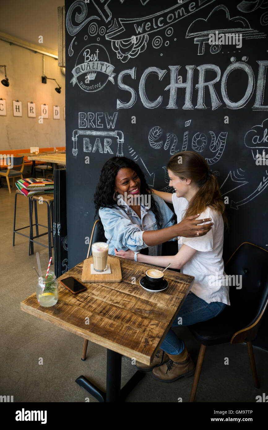 Two friends meeting in cafe, embracing Stock Photo - Alamy