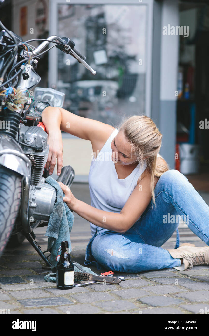 Young woman cleaning motorbike Stock Photo - Alamy