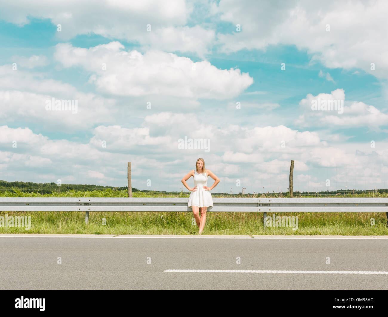 Young woman in white dress standing at the roadside Stock Photo - Alamy