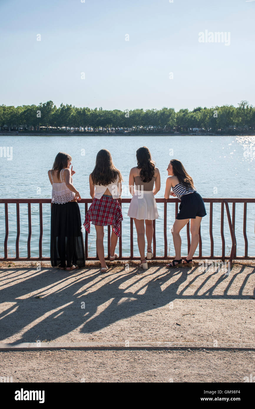 Back view of four friends standing at sunlight in front of water Stock ...