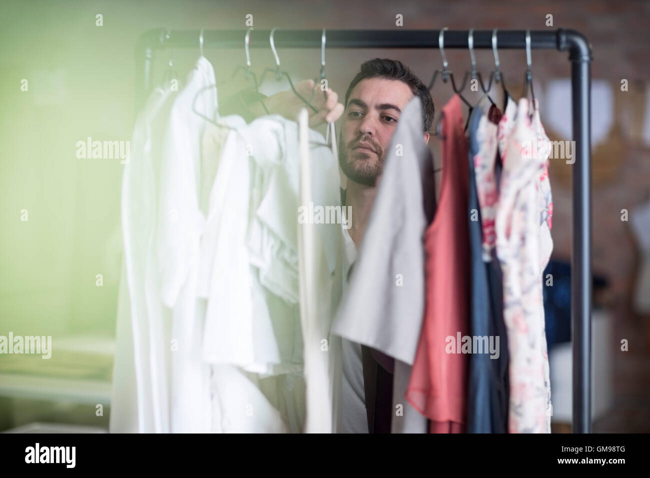 Man looking at clothes stand in boutique Stock Photo - Alamy