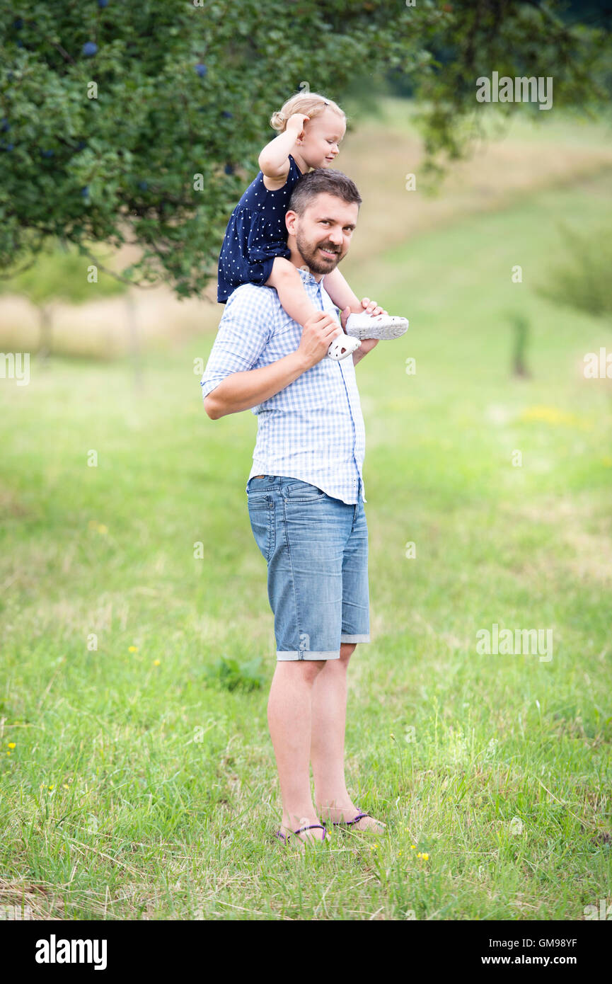 Happy father carrying little daughter on shoulders in nature Stock Photo - Alamy