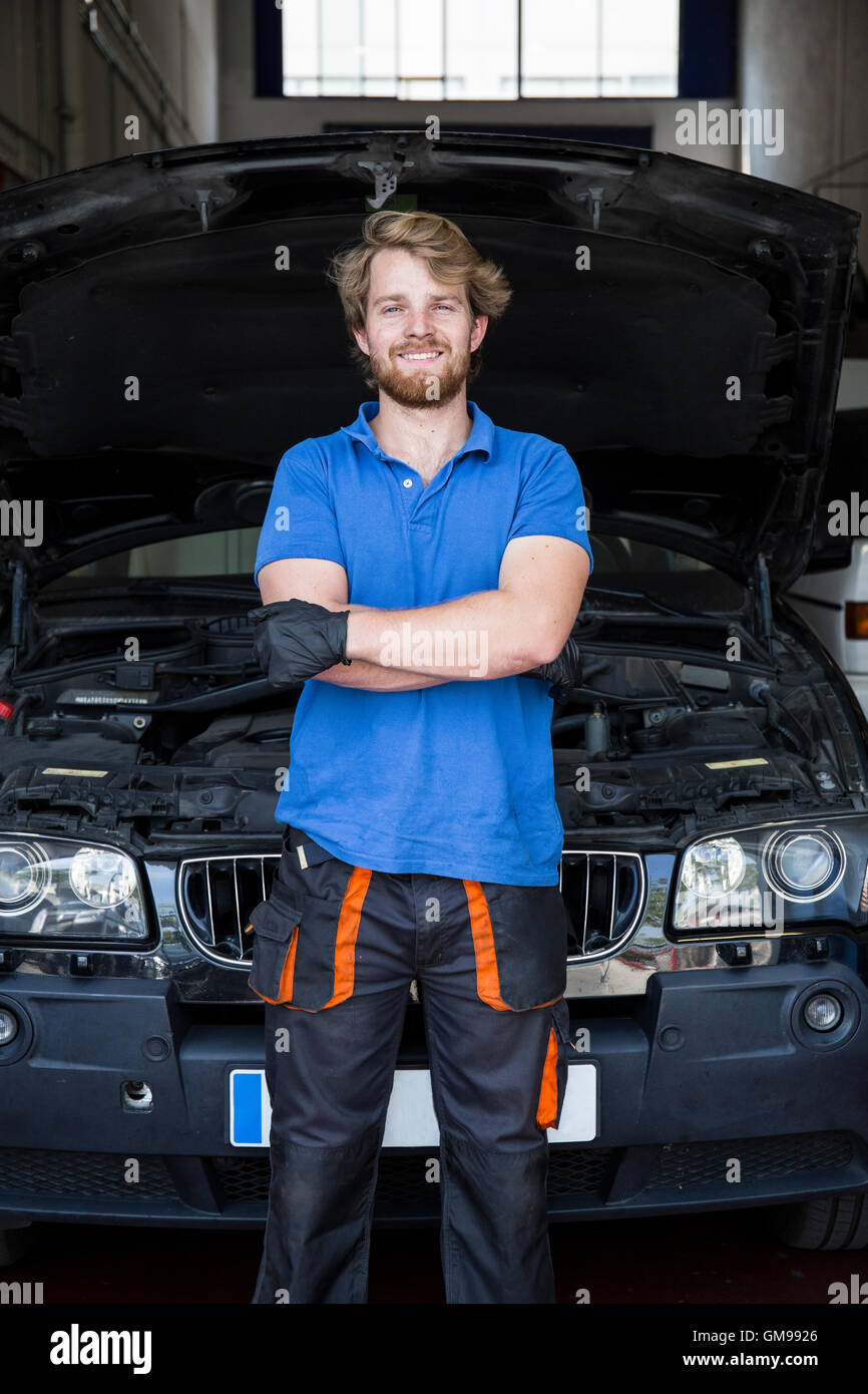 Confident mechanic standing in his car workshop with arms crossed Stock ...