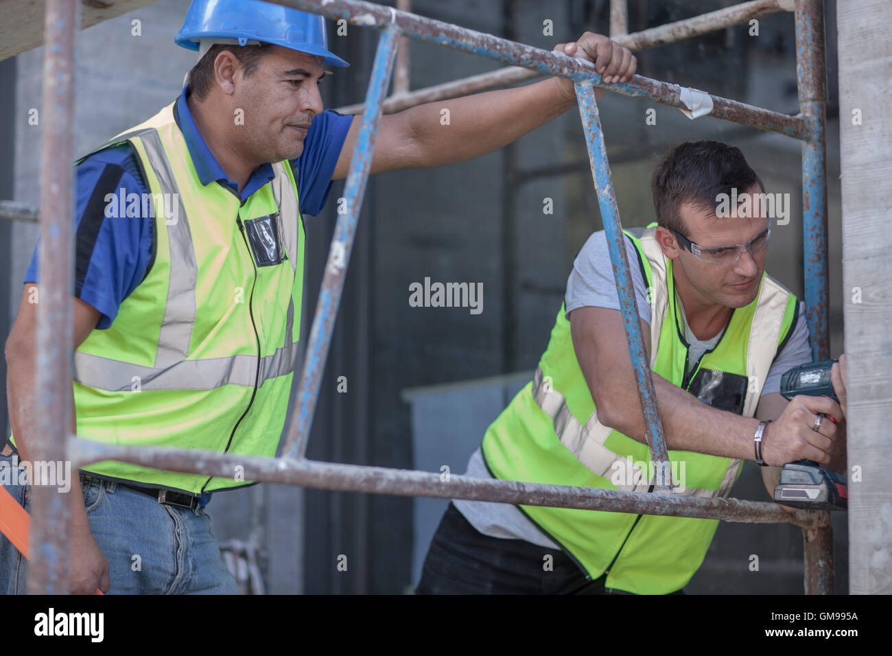 Two construction workers on scaffolding working on construction site ...