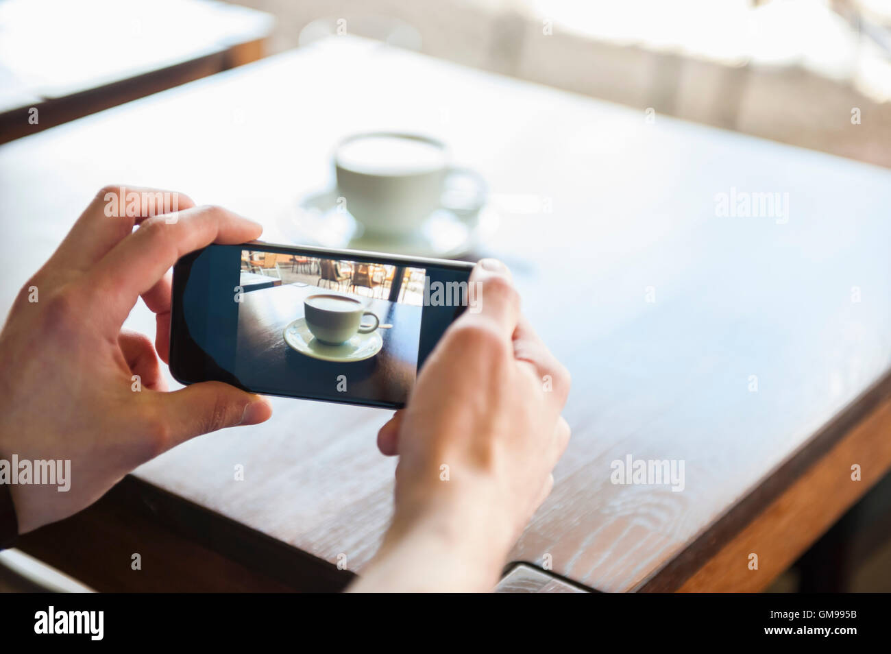 Man taking cell phone picture of cup of coffee Stock Photo - Alamy