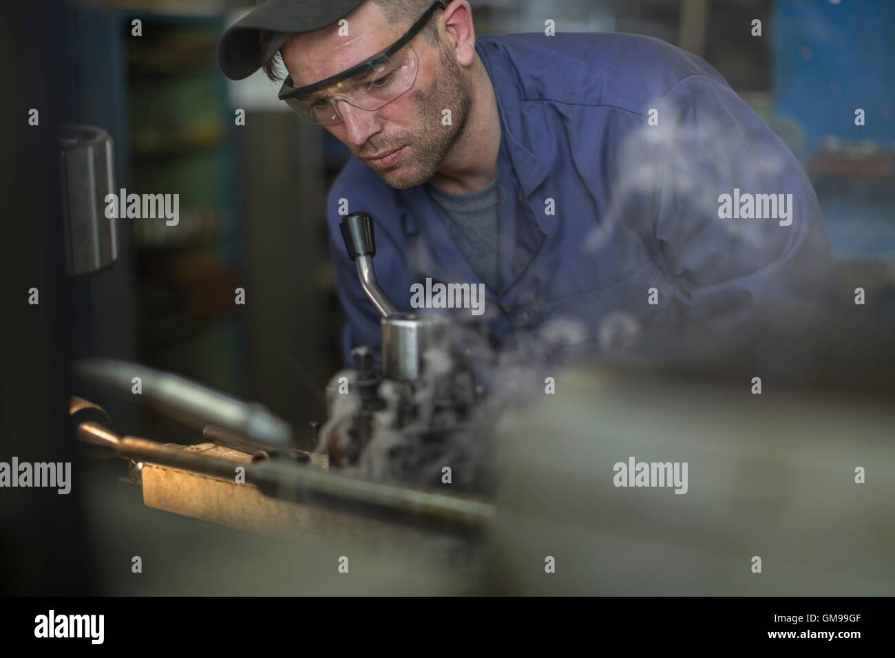 Mechanic wearing safety goggles using machine in workshop Stock Photo ...