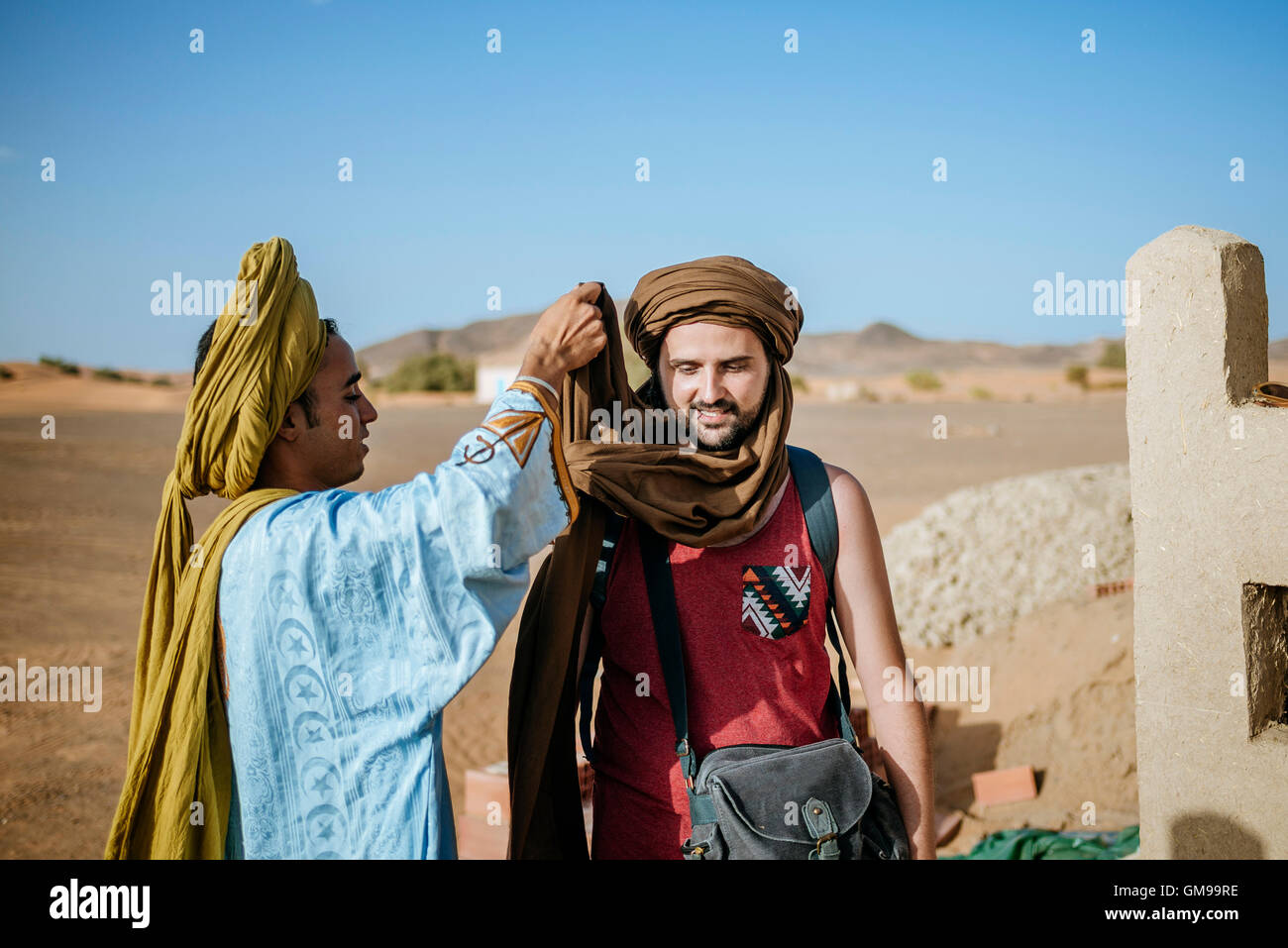 Berber guide helping touist wrapping a turban Stock Photo - Alamy