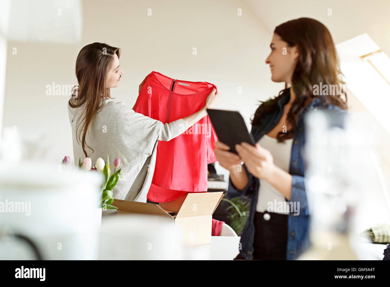 Two women with digital tablet and parcel with garment Stock Photo - Alamy