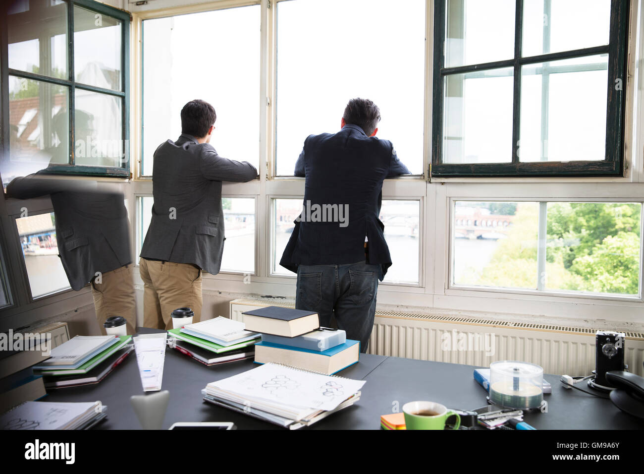 Two businessmen looking out of window Stock Photo - Alamy