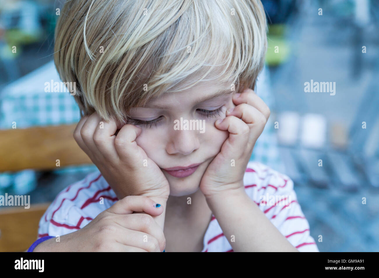 Portrait of little blond boy with head in his hands Stock Photo - Alamy
