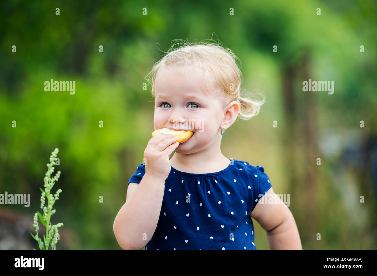 Portrait of little blond girl eating pastry Stock Photo - Alamy