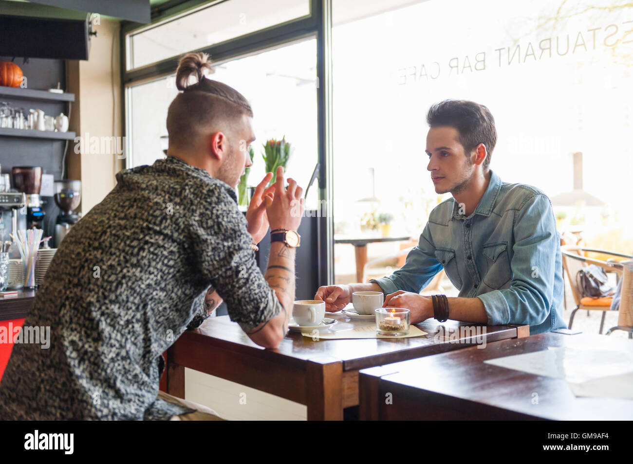 To young men socializing in a cafe Stock Photo - Alamy