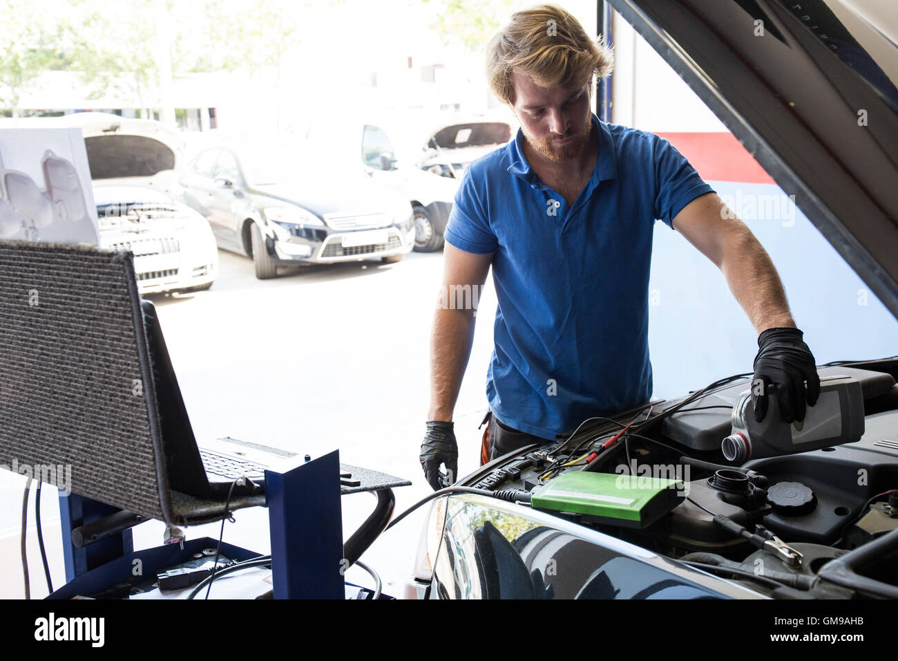 Mechanic refilling oil in a car Stock Photo - Alamy