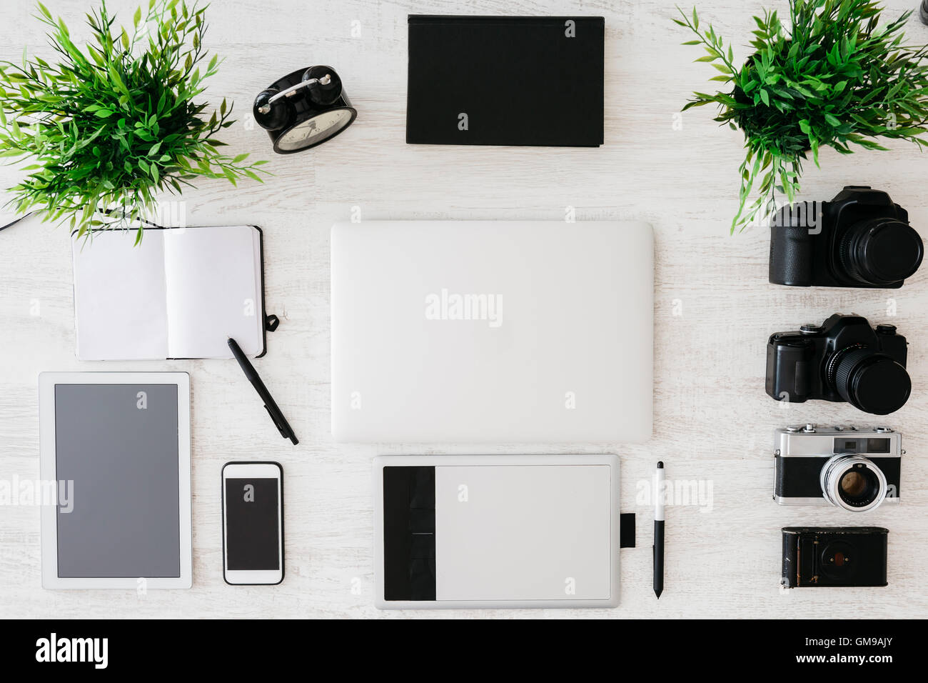 Desk of photographer with notebook, laptop, cameras, tablet and ...