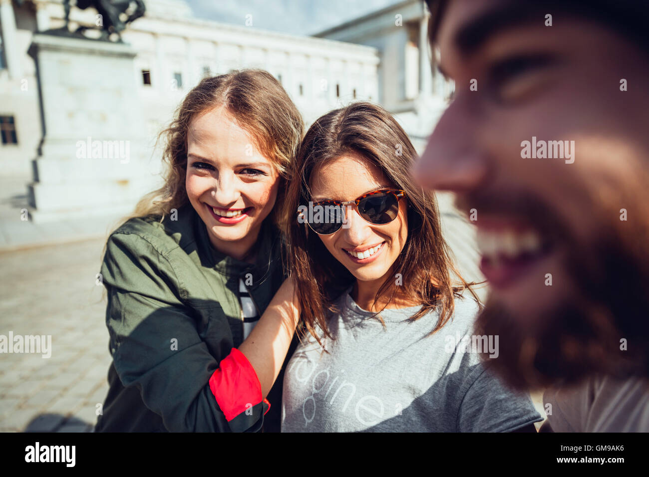 Austria, Vienna, three friends having fun in front of the parliament ...