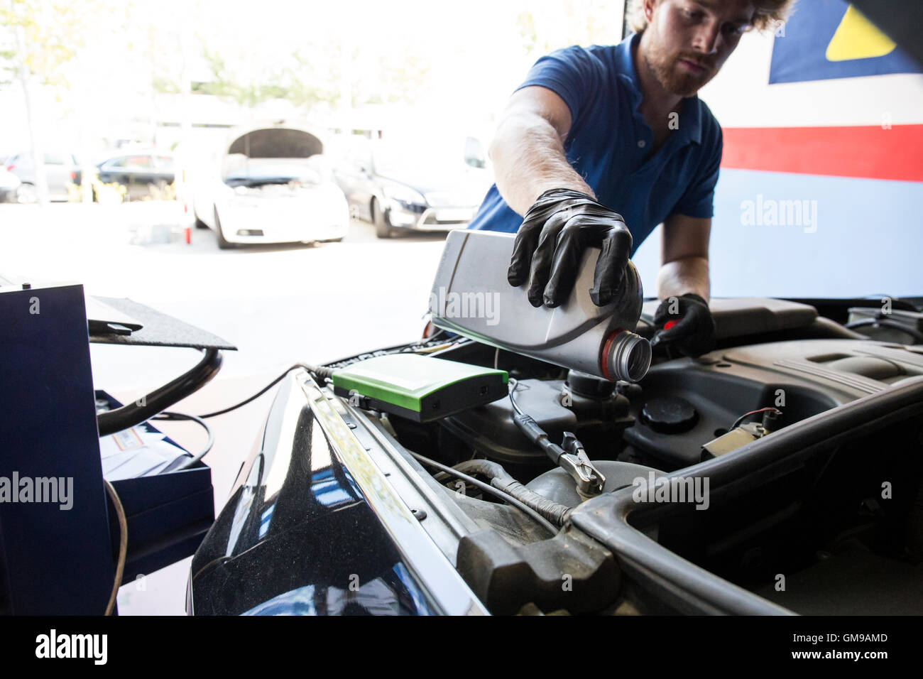 Mechanic refilling oil in a car Stock Photo - Alamy