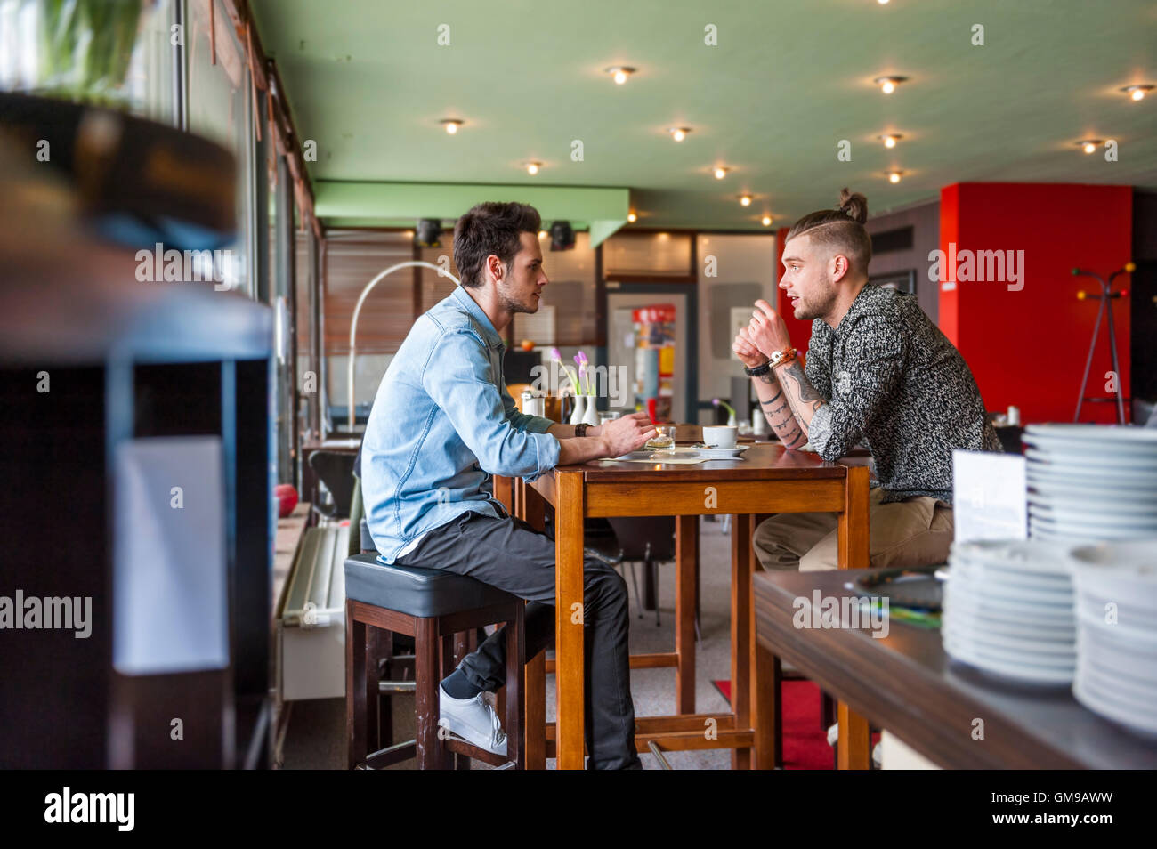 To young men socializing in a cafe Stock Photo - Alamy