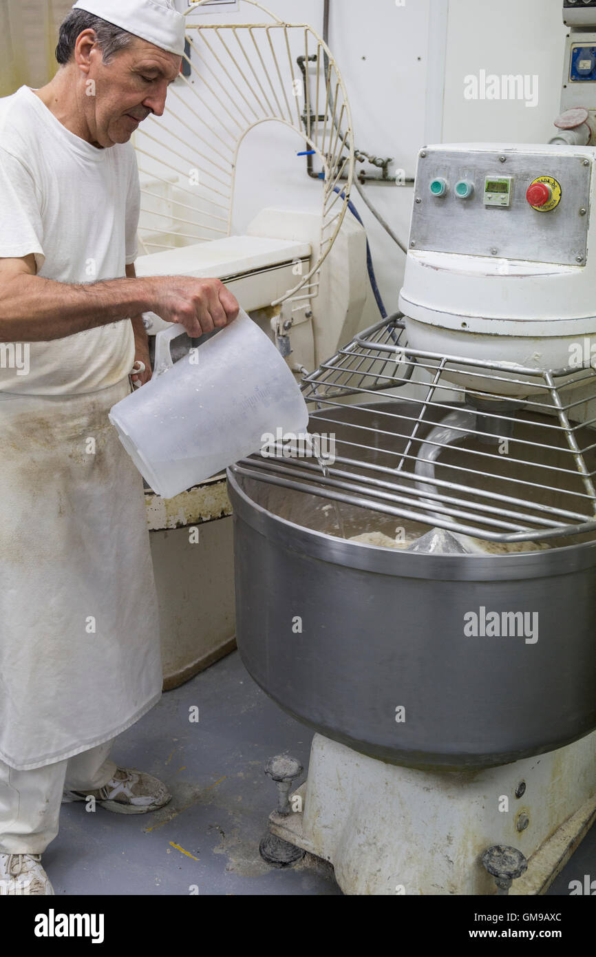 Baker pouring water in an industrial kneading machine Stock Photo - Alamy