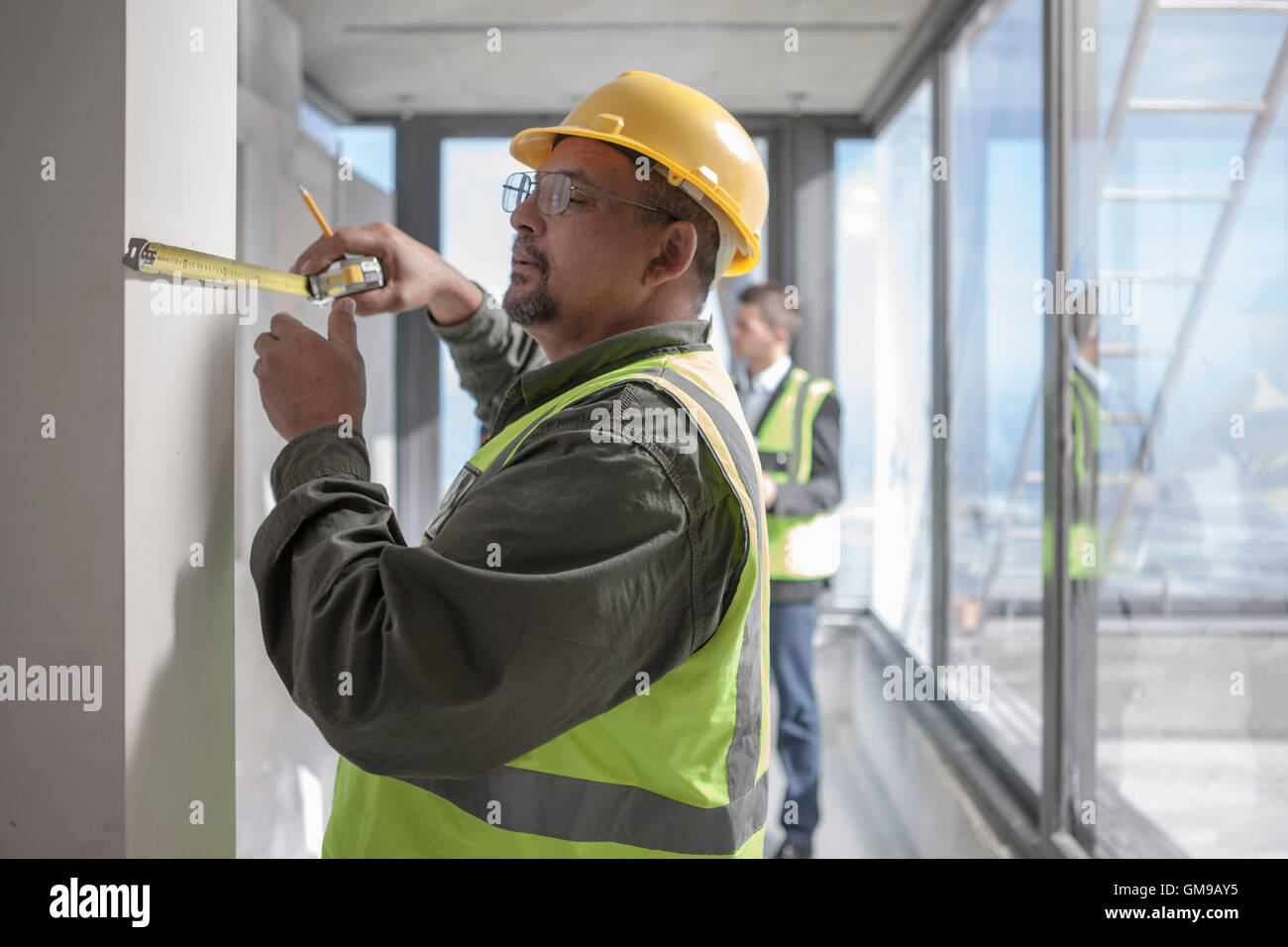 Construction worker measuring on construction site Stock Photo - Alamy