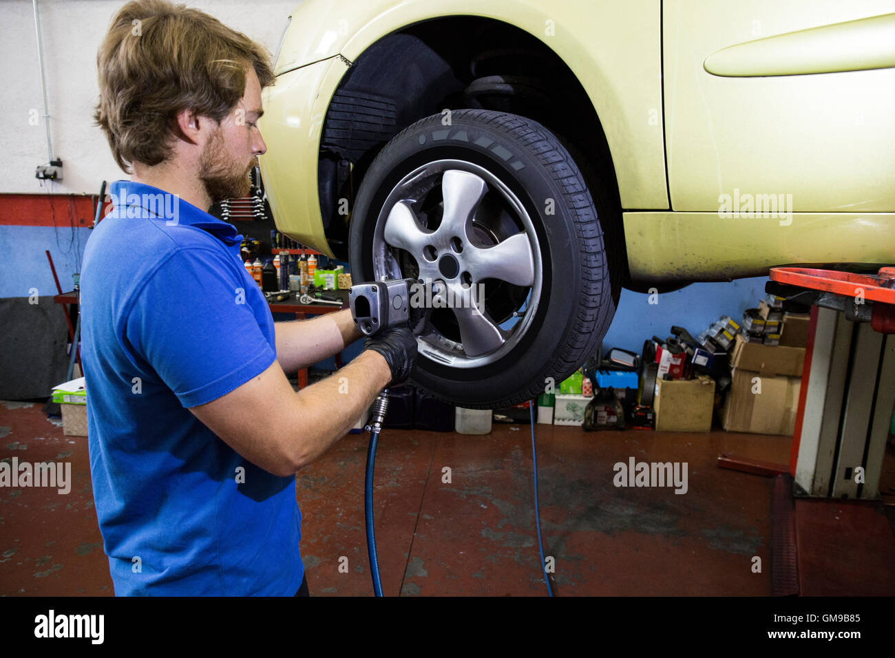 Mechanic fixing a car wheel in a workshop Stock Photo - Alamy