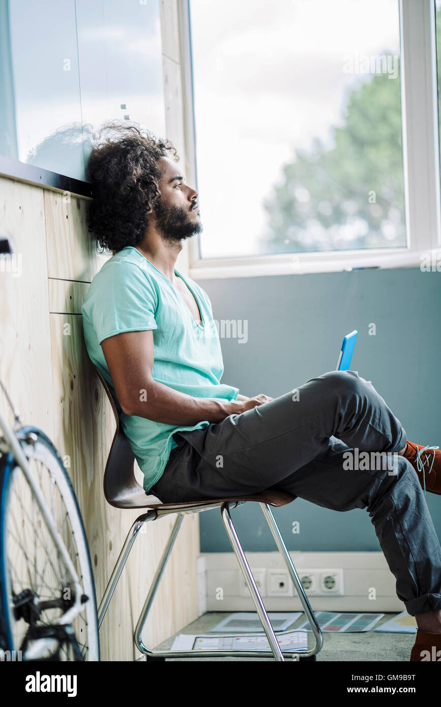 Young designer sitting on chair, using laptop Stock Photo - Alamy