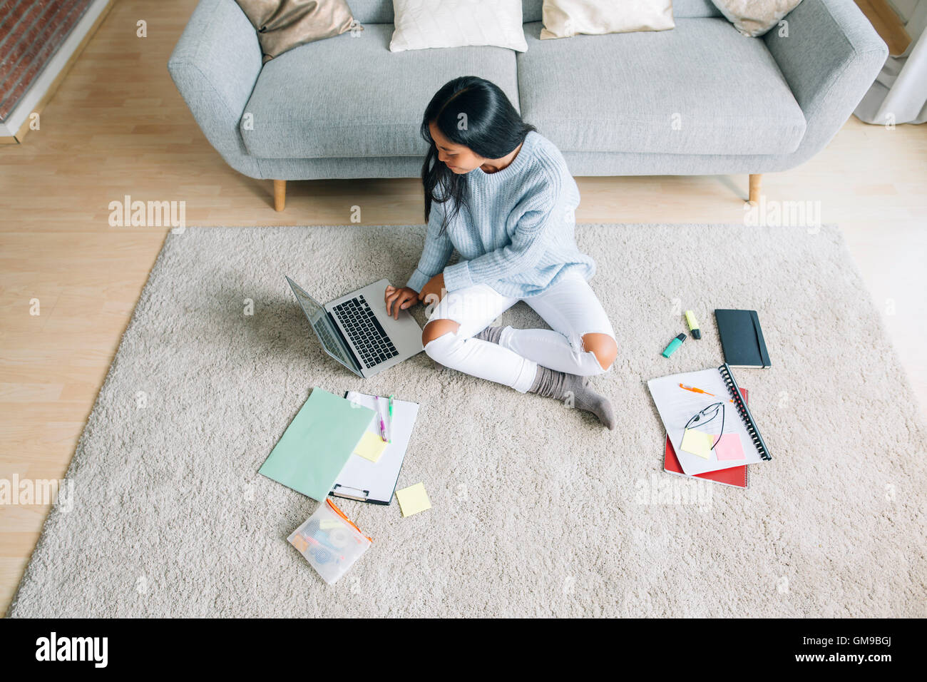 Young woman sitting on floor in the living room using laptop Stock ...