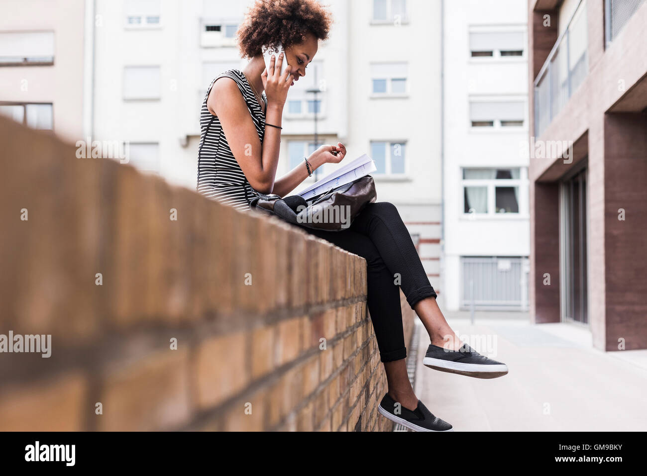 Young woman sitting on wall telephoning with cell phone Stock Photo - Alamy