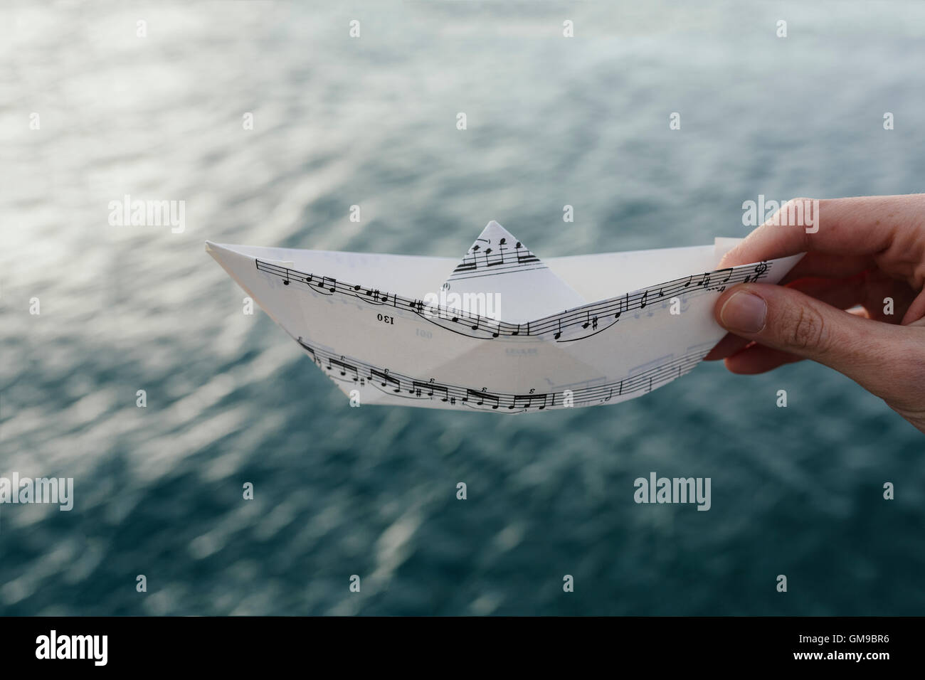 Hand at the water holding paper boat made of music sheet Stock Photo ...