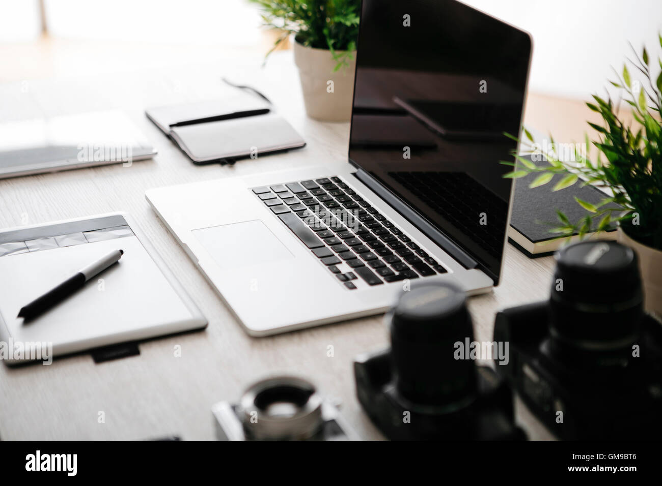 Desk of photographer with laptop, cameras, tablet and graphics tablet ...