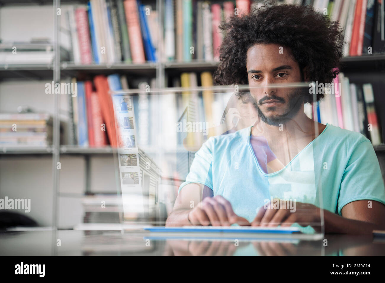 Young man working in library, using futuristic computer Stock Photo - Alamy