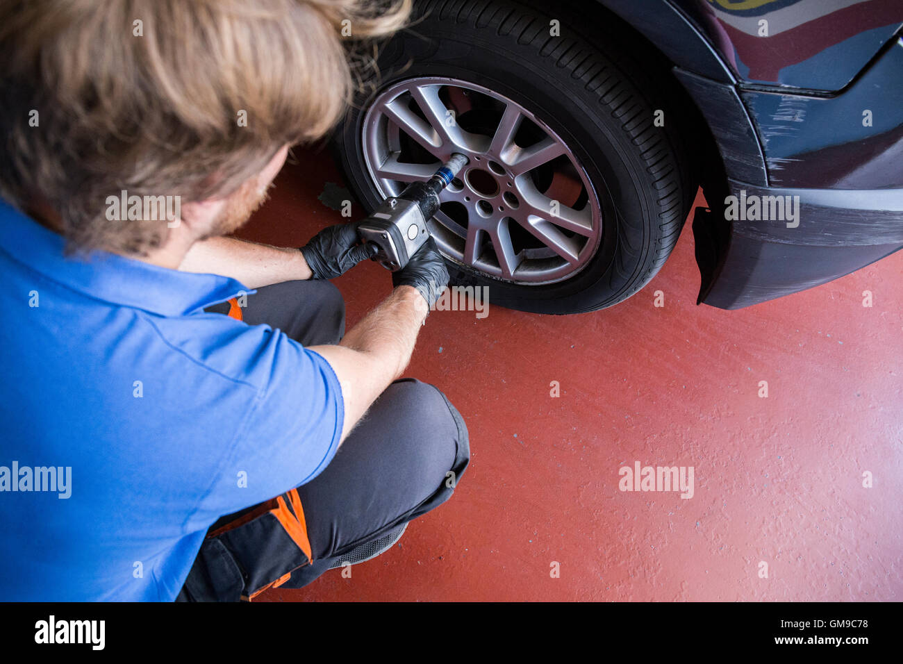 Mechanic fixing a car wheel in a workshop Stock Photo - Alamy