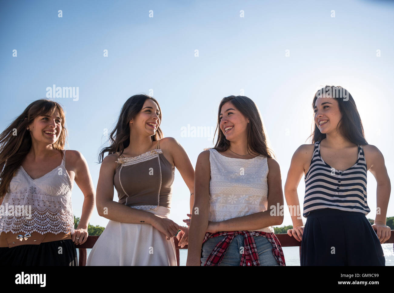 Four happy friends standing side by side at sunlight Stock Photo - Alamy