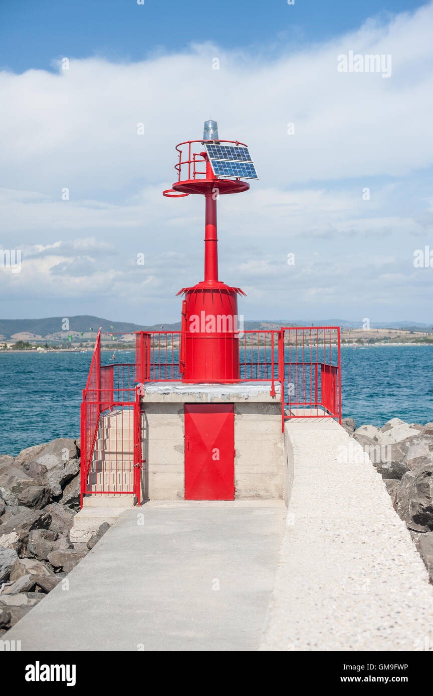 Red marine beacon light with solar panels energy on harbor dock, sea ...