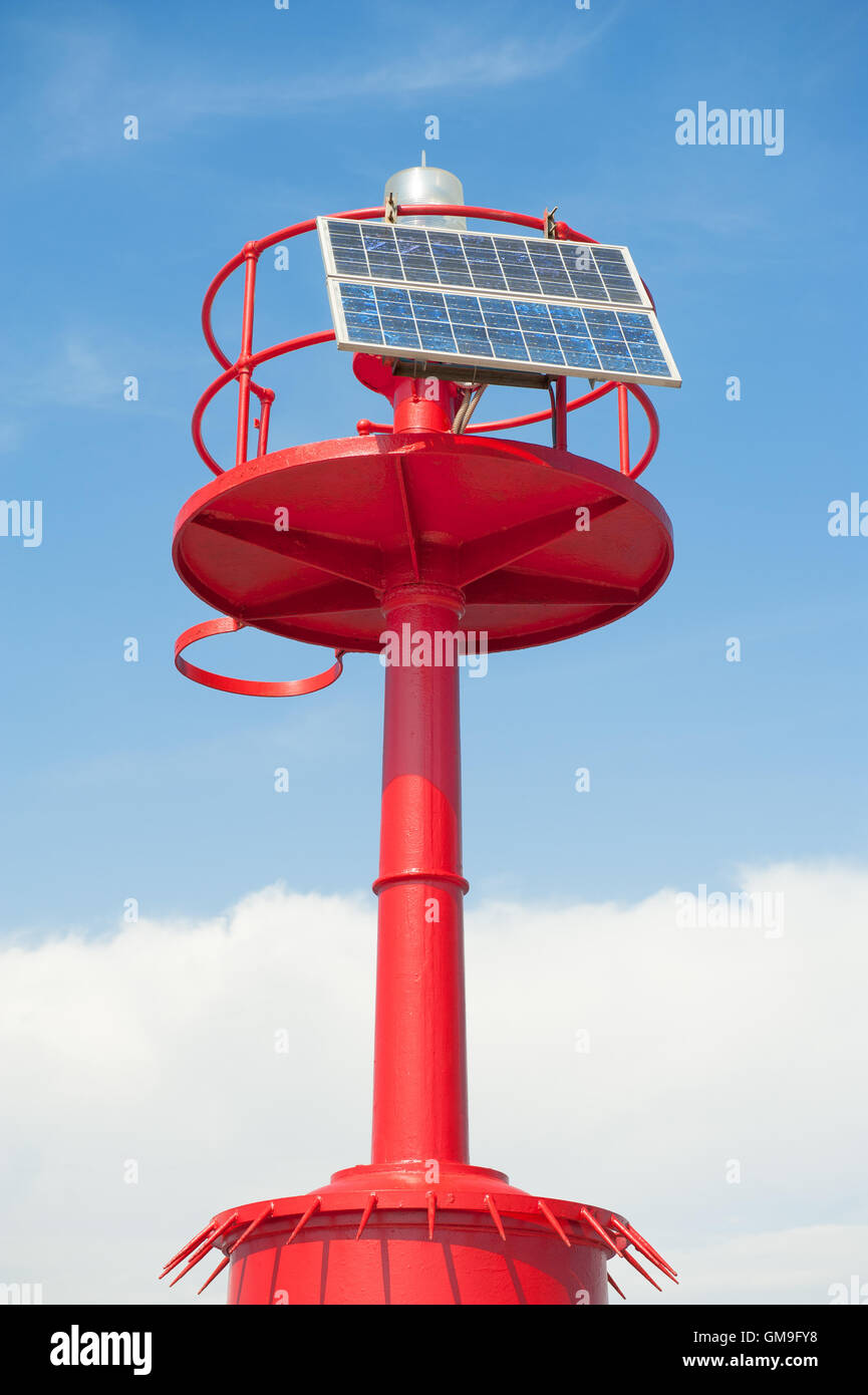 Red marine beacon light with solar panels energy close up on blue ...
